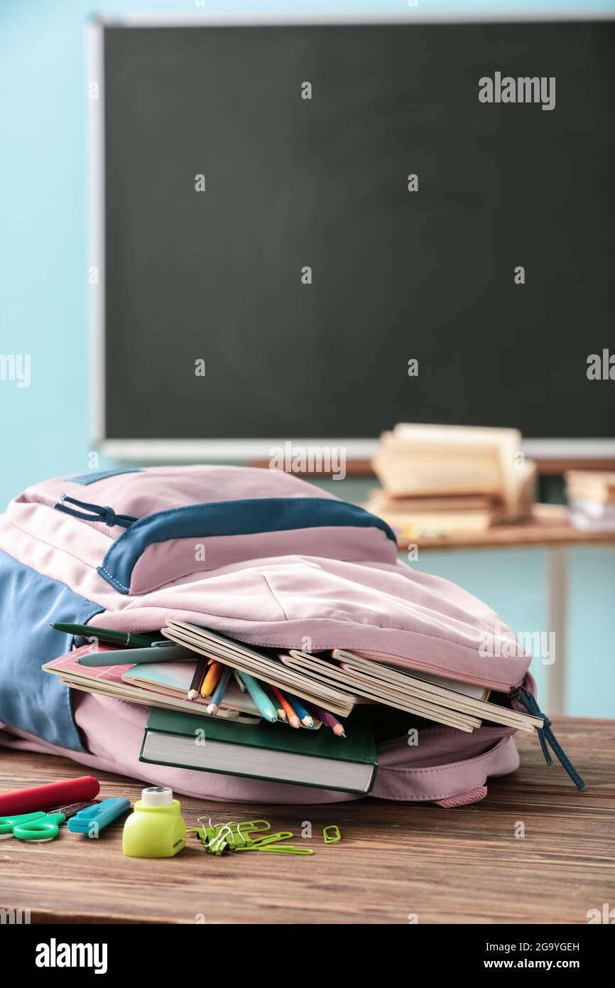 School backpack with stationery on table in classroom Stock Photo - Alamy