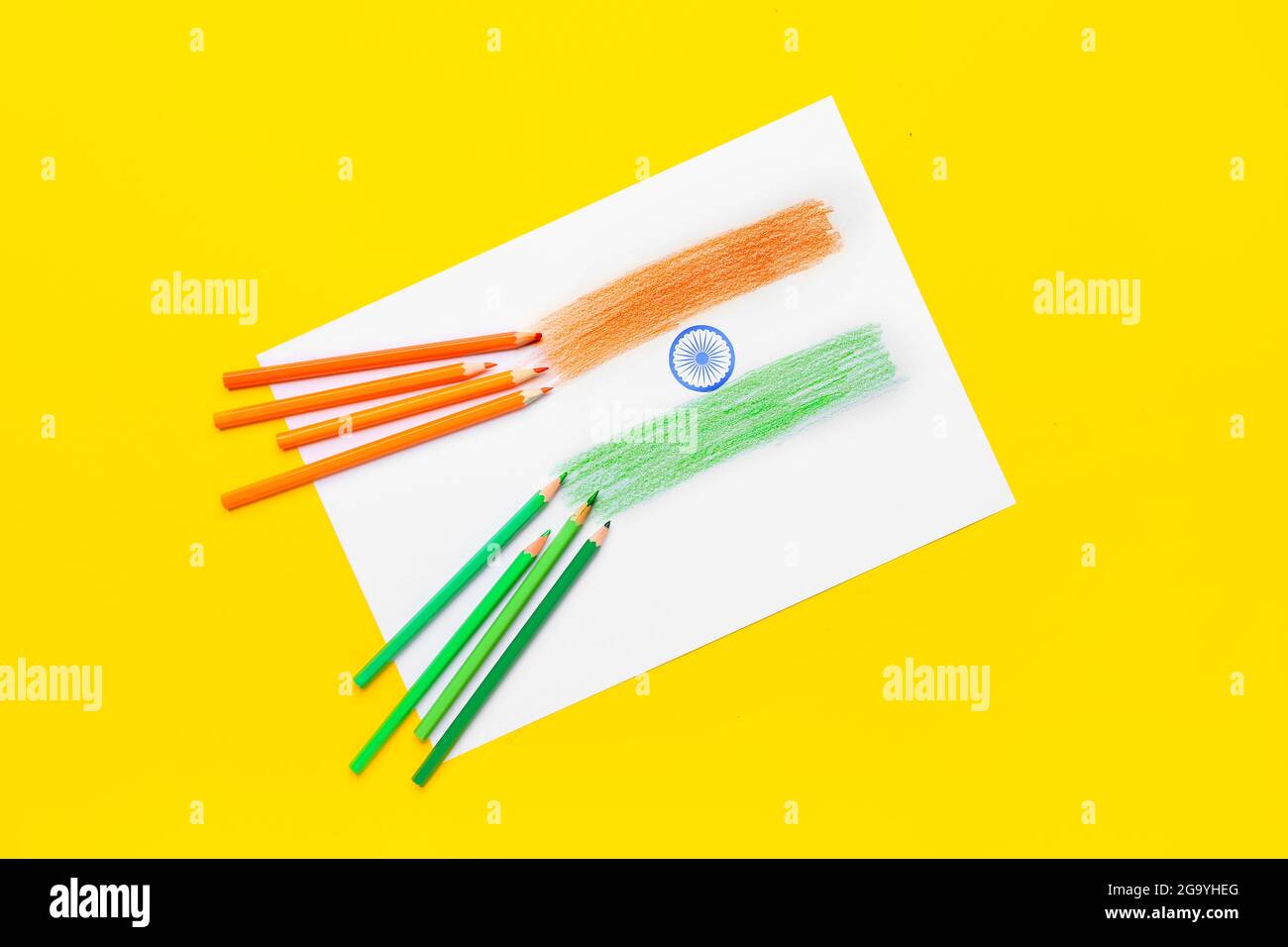Paper sheet with drawn Indian flag and pencils on color background ...