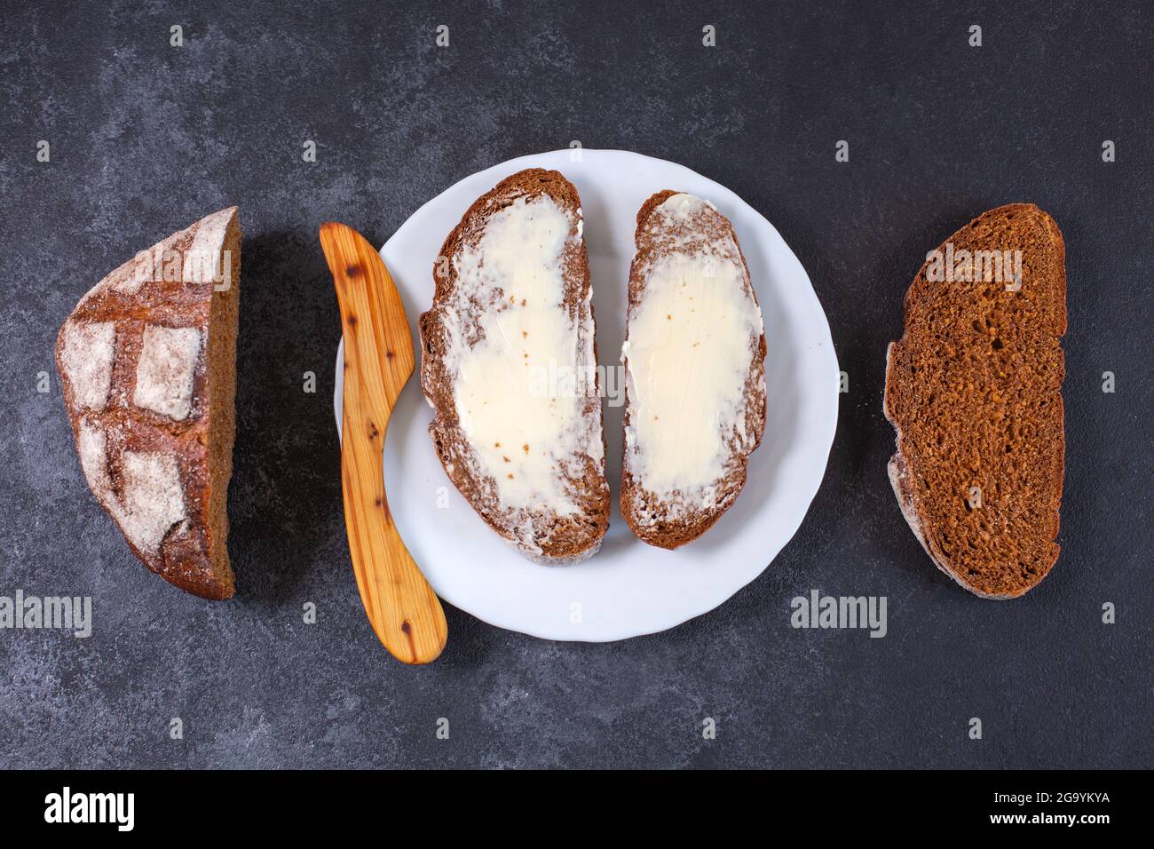 Homemade fresh wheat-rye bread with butter with a wooden butter knife ...