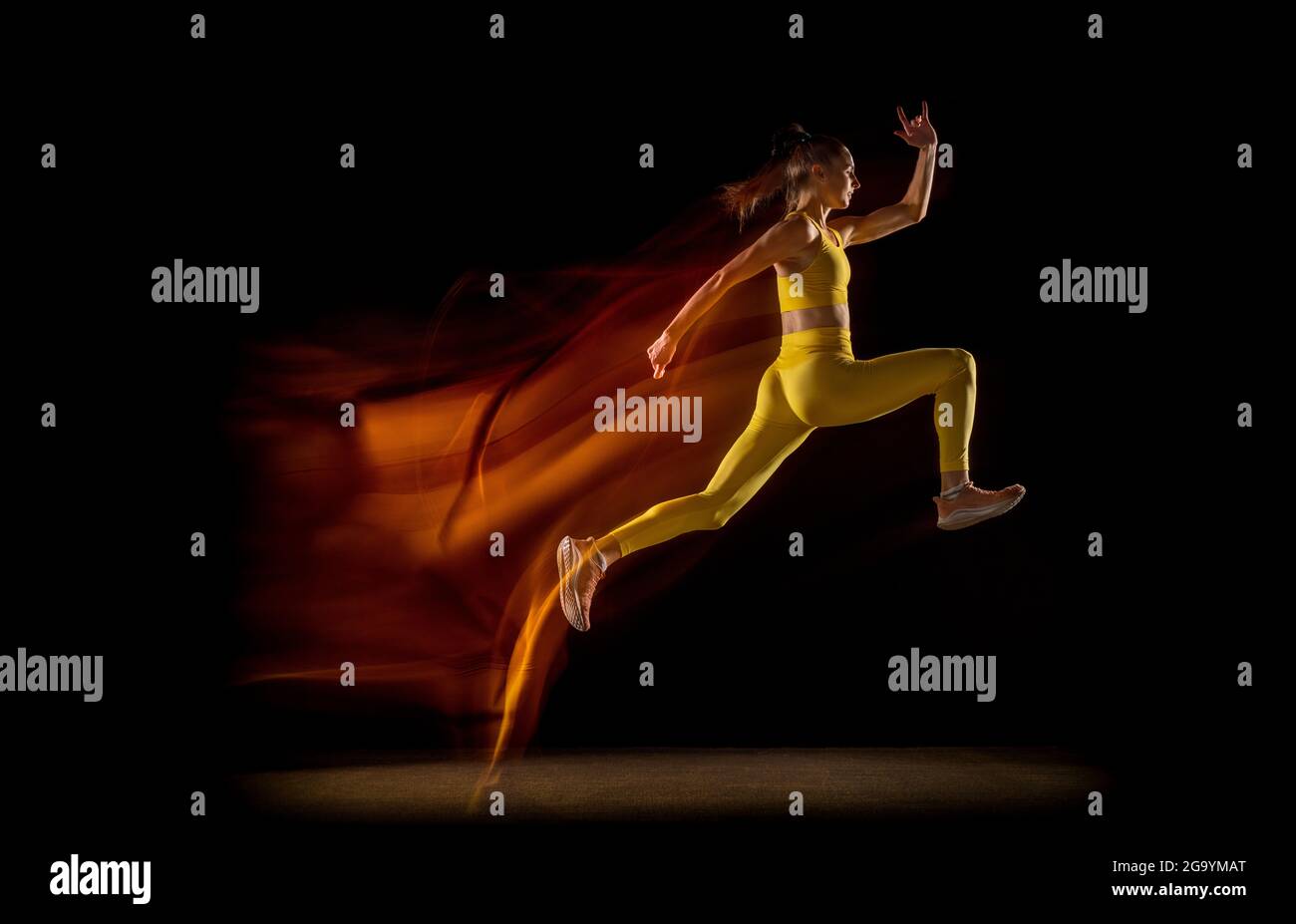 One young woman, female athlete training isolated over black studio ...