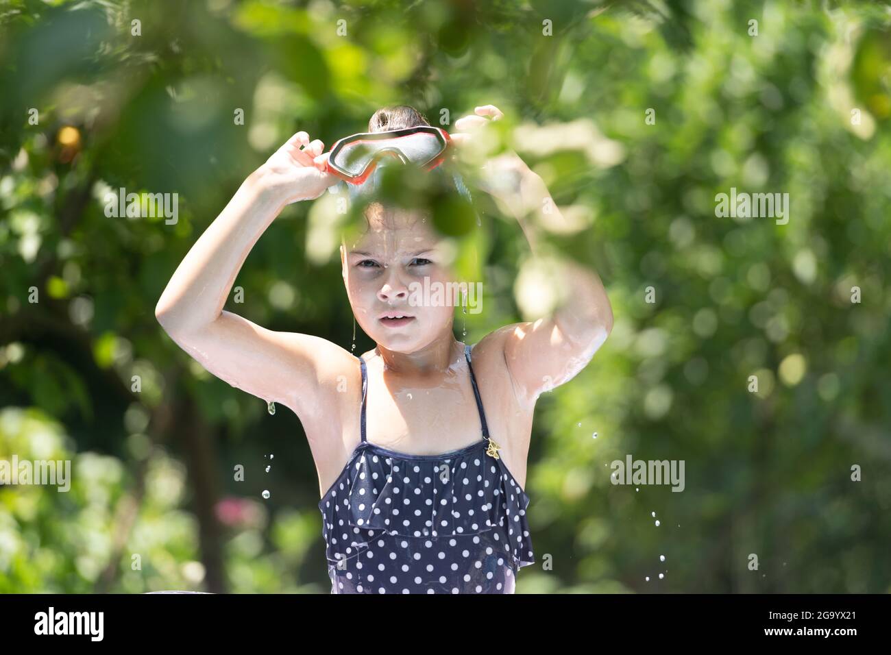 Enjoying a summer day. Wet child take off goggles. Girl go sunbathing ...