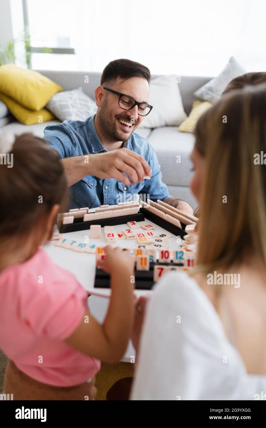 Happy young parents and children having fun, playing board game at home ...