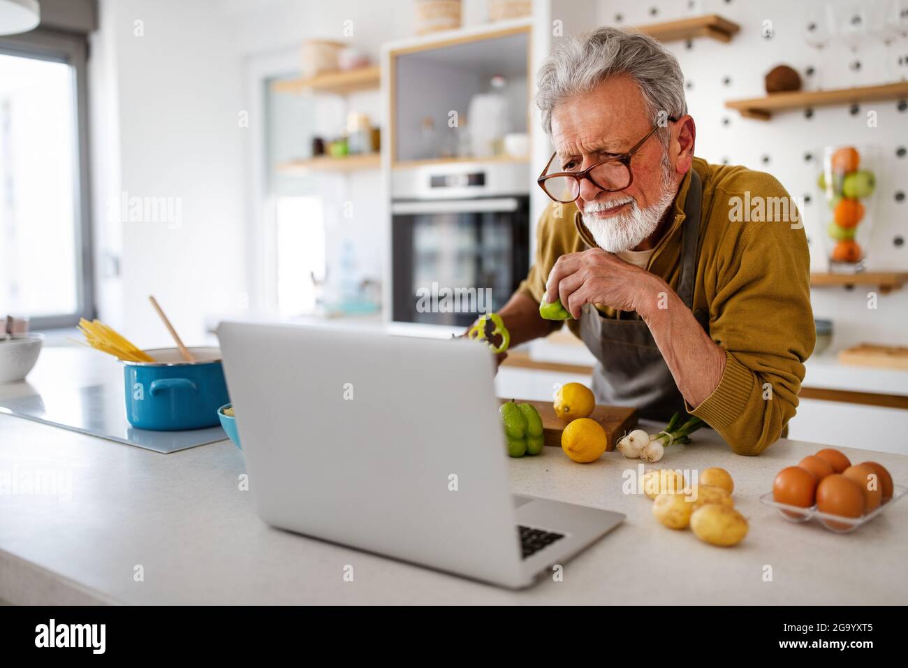 Happy retired senior man cooking in kitchen. Retirement, hobby people ...