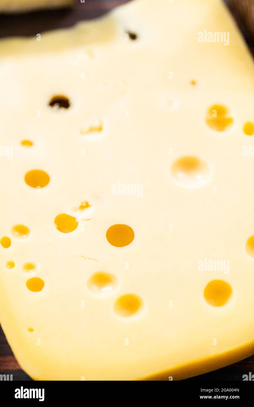 Large wedge of semi soft part-skim swiss cheese on a dark wooden background Stock Photo - Alamy