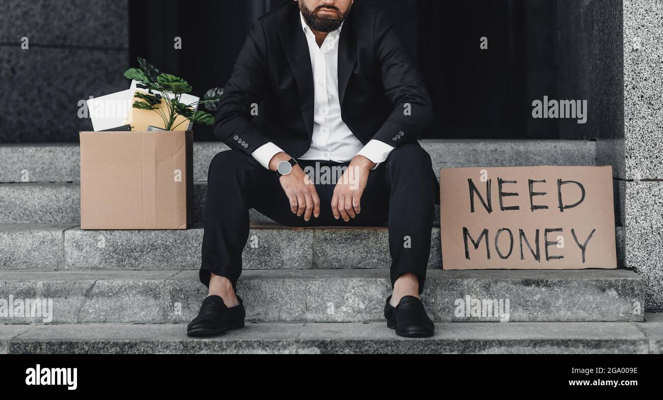 Hopeless businessman with paper poster saying need money and box of ...