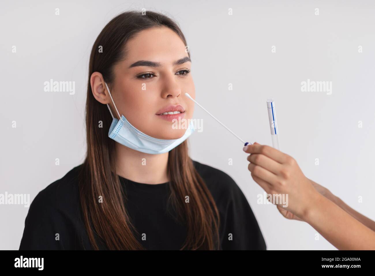 Doctor making covid-19 nasal PCR test for young female patient over ...