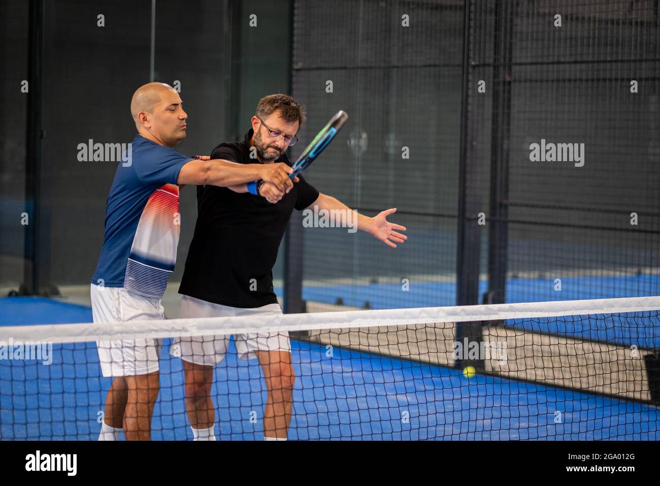 Monitor teaching padel class to man, his student - Trainer teaches boy ...