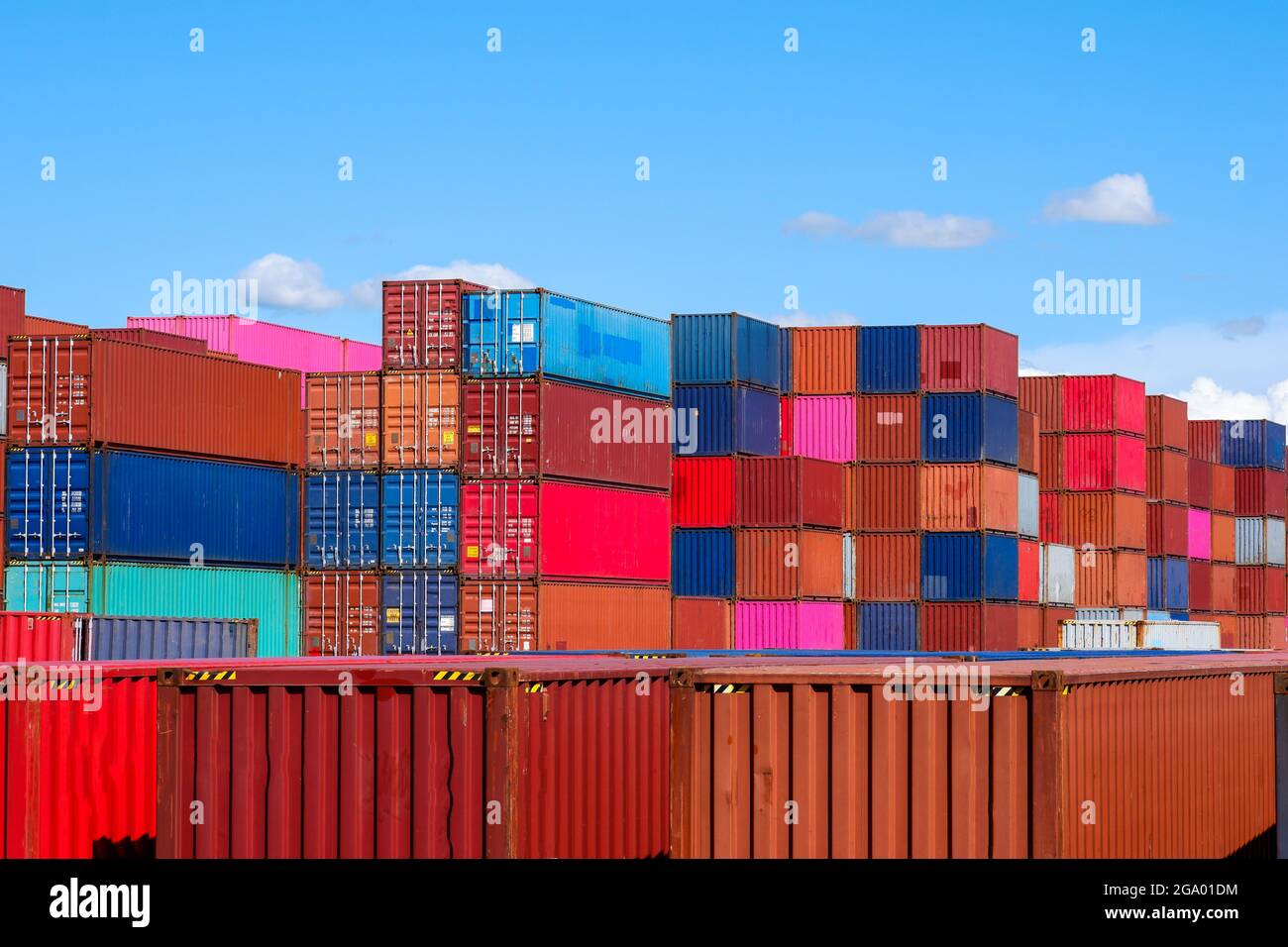 Containers piled up in a cargo yard against a blue sky. transport ...