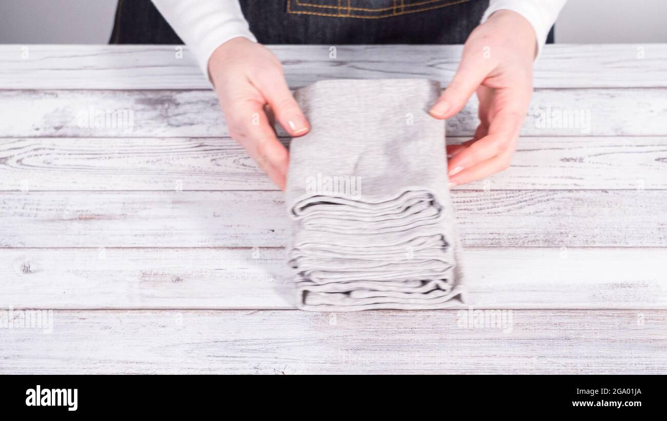 Step by step. Folding natural color linen dinner napkin on a wooden ...