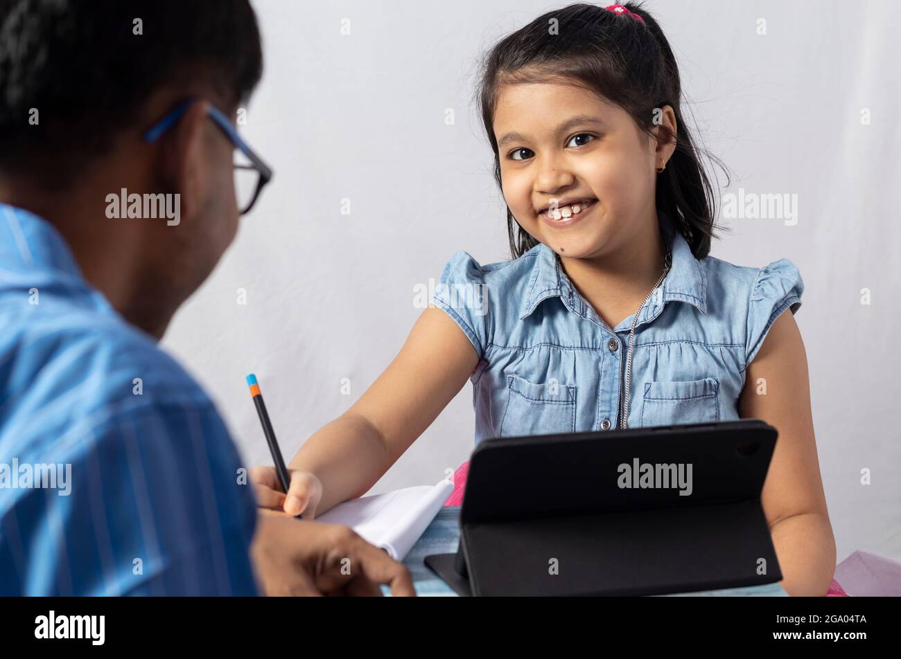 An Indian girl student studying and having fun with tablet in front of ...