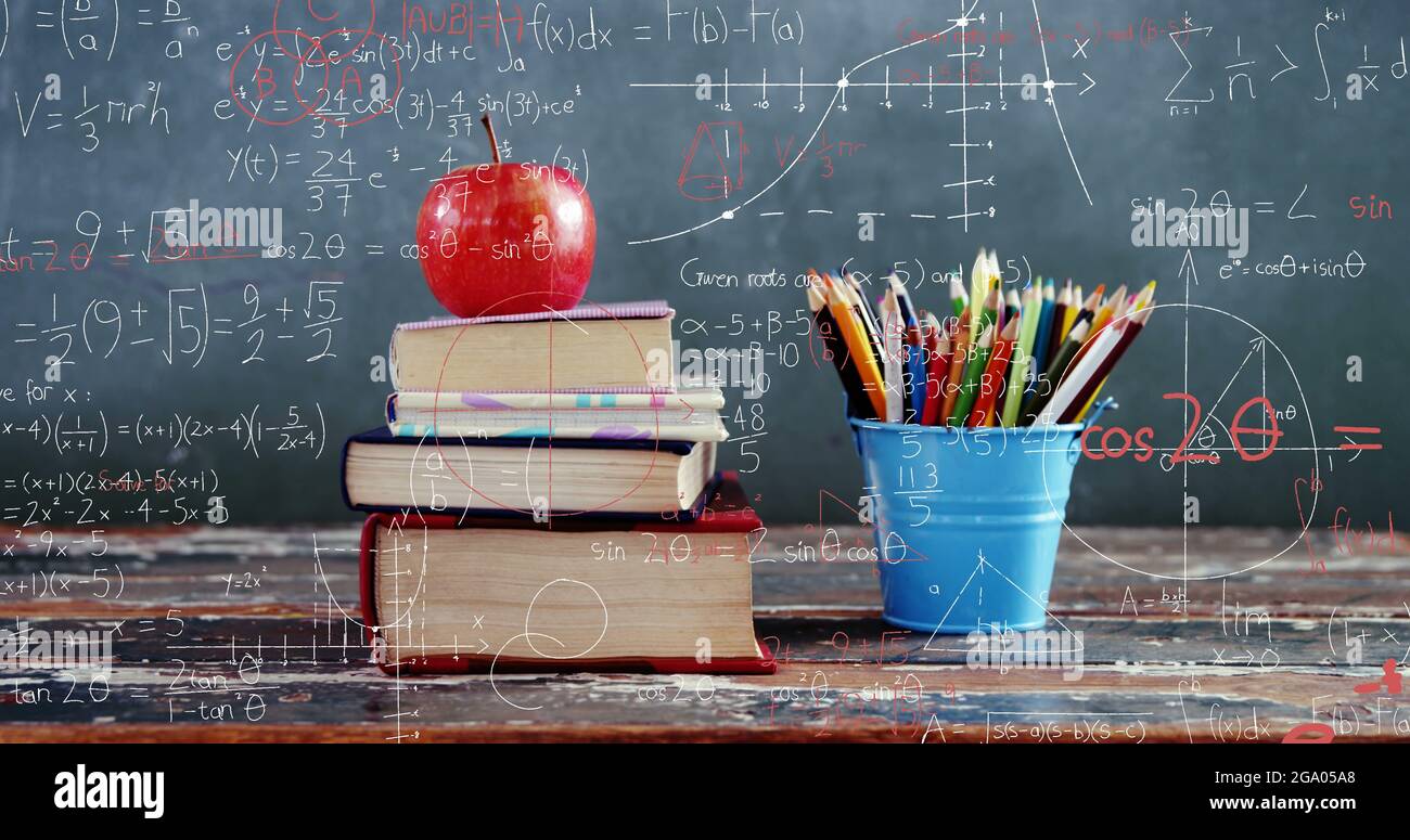 Mathematical equations floating against apple on stack of books and ...