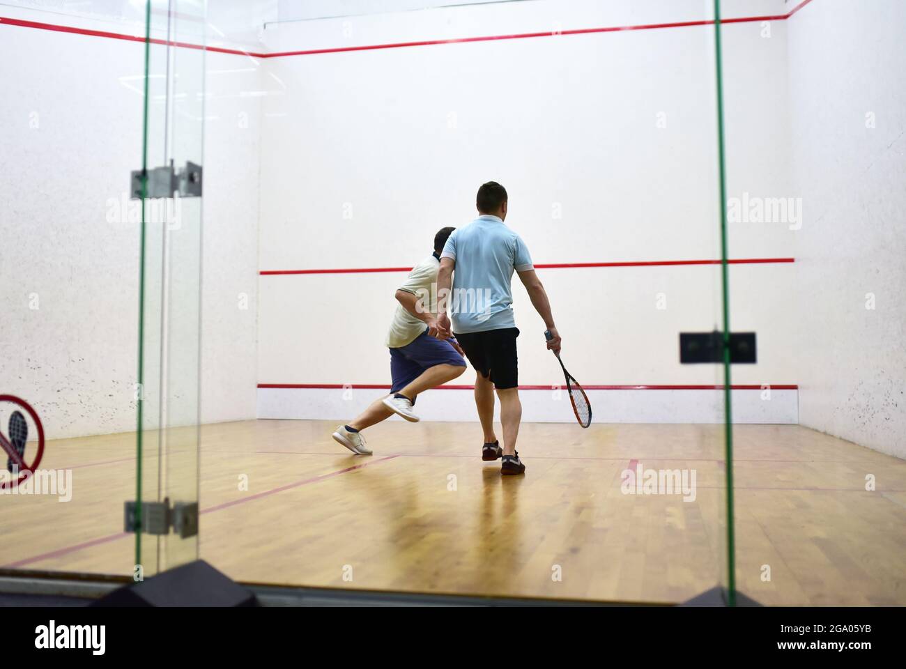 Squash player in action reaching on squash court. Out of focus ...