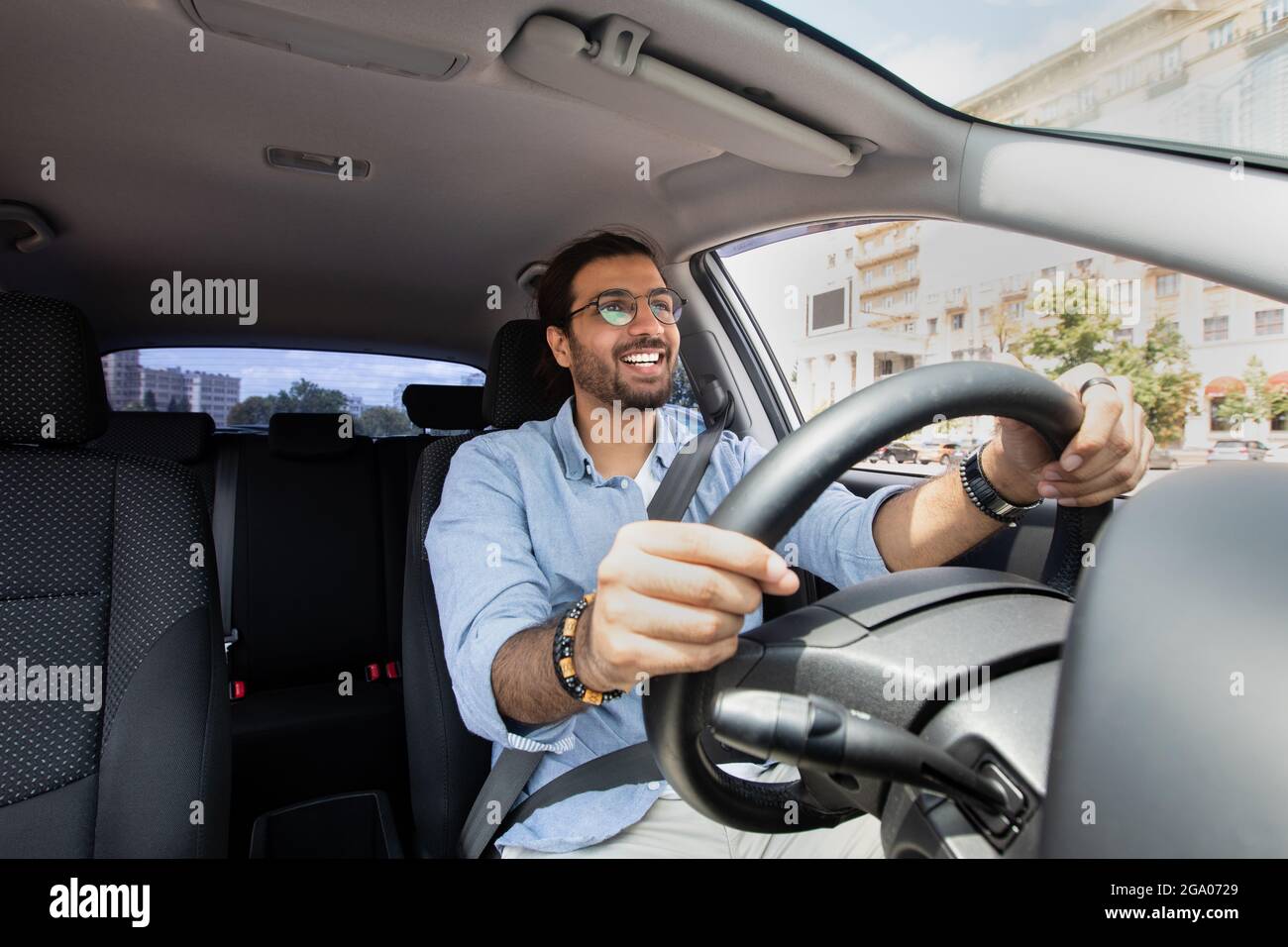 Joyful middle-eastern man driving car, shot from front pannel Stock ...