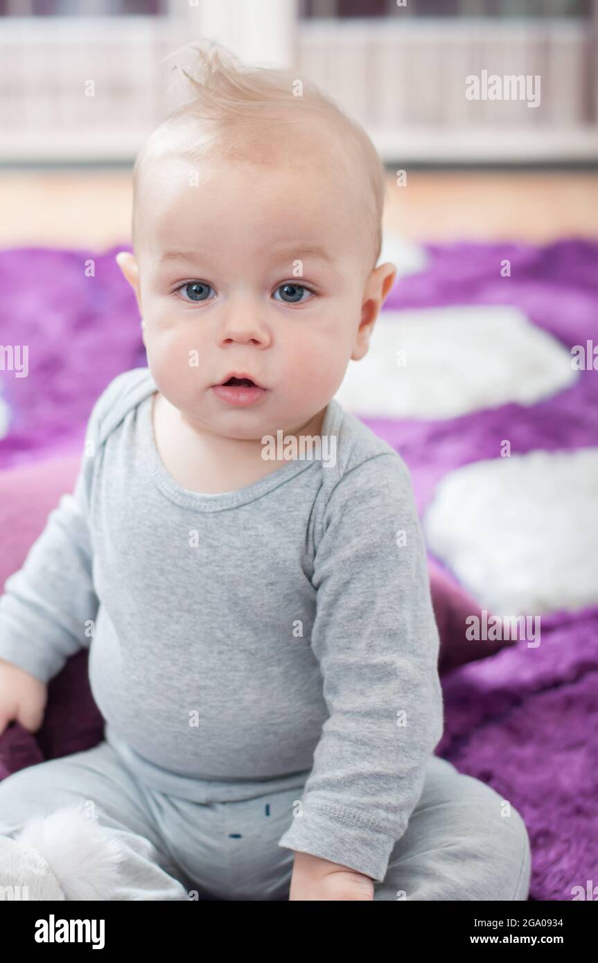 Happy baby boy sitting on the floor and posing. Looking at camera Stock ...