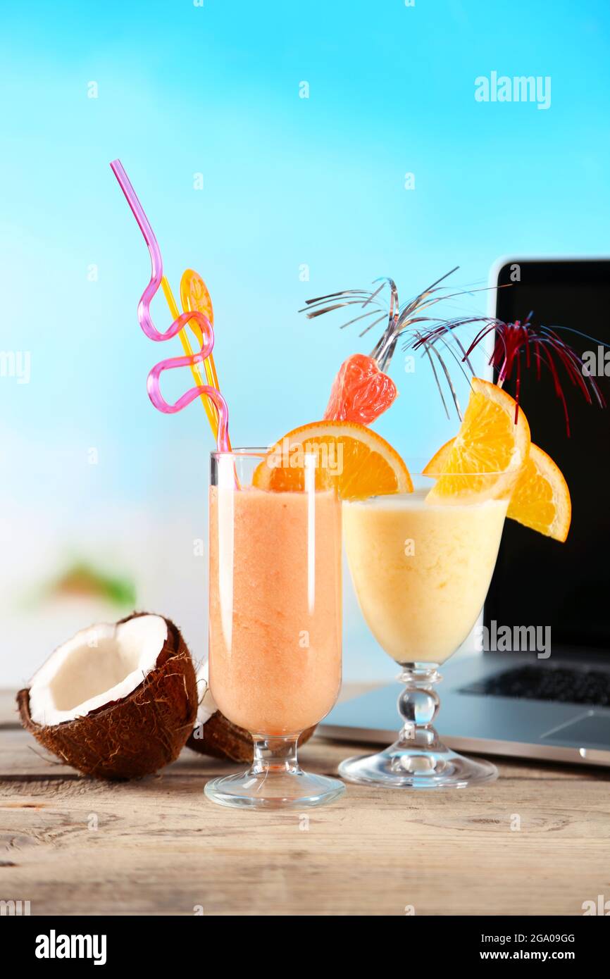 Laptop and glasses of summer cocktails on wooden table, on bright ...