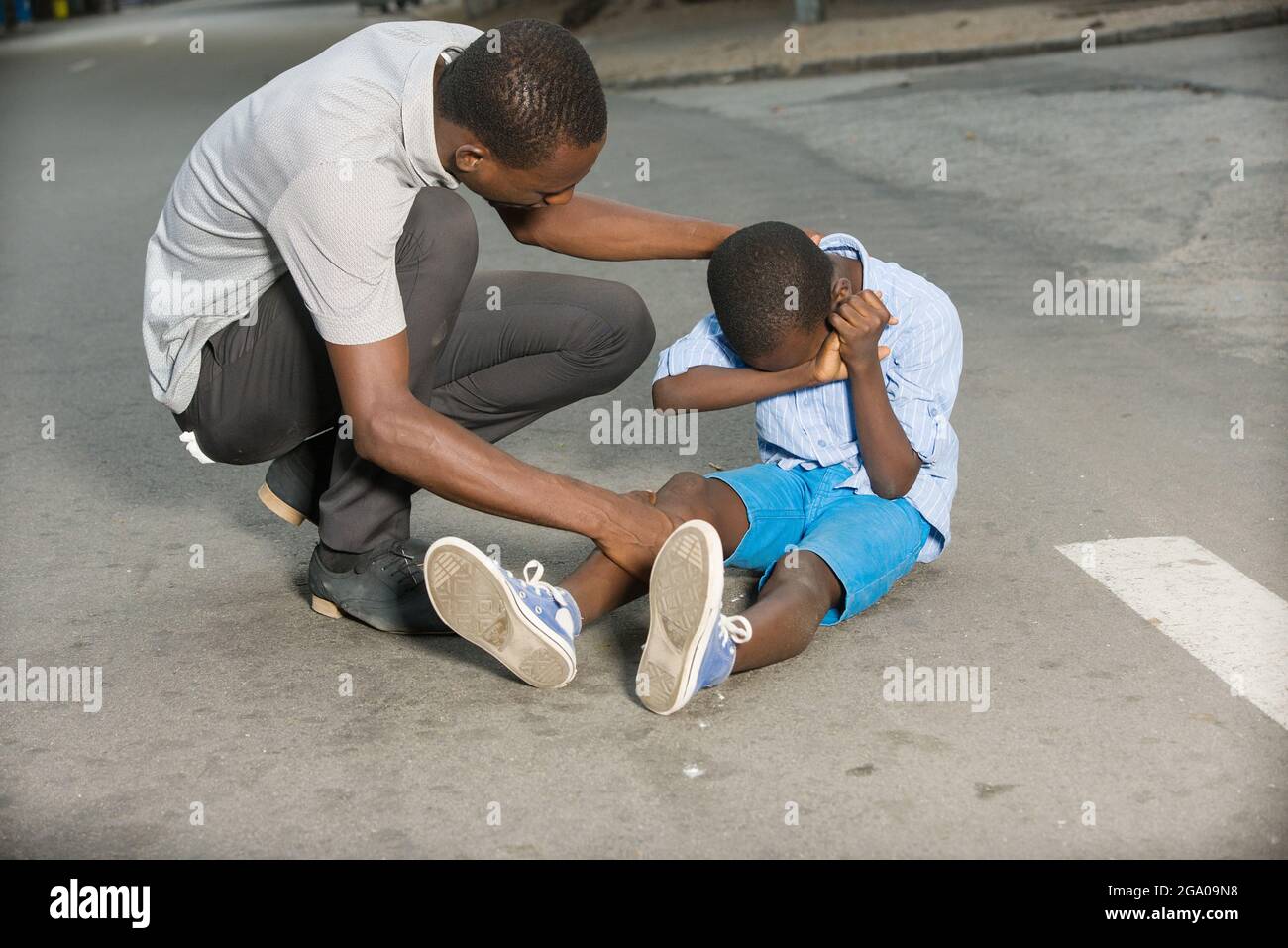 Father comforting his son crying, child fallen on the road having a ...