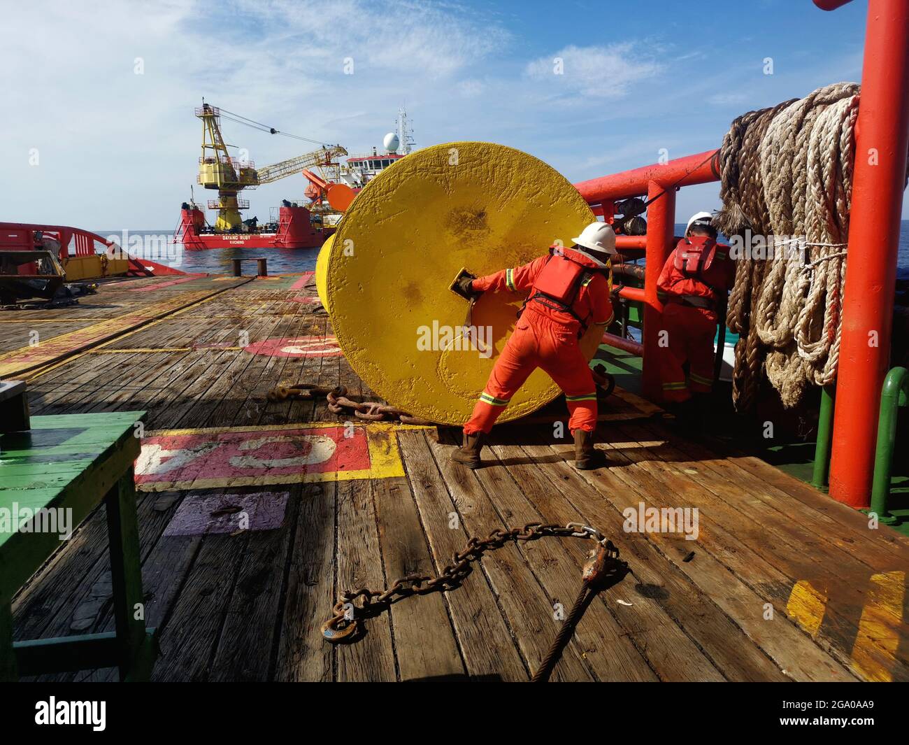 marine crew working on deck during anchor handling operation near oil ...