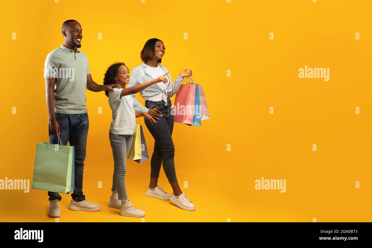 Family shopping. Pretty girl pointing finger at free space, showing ...