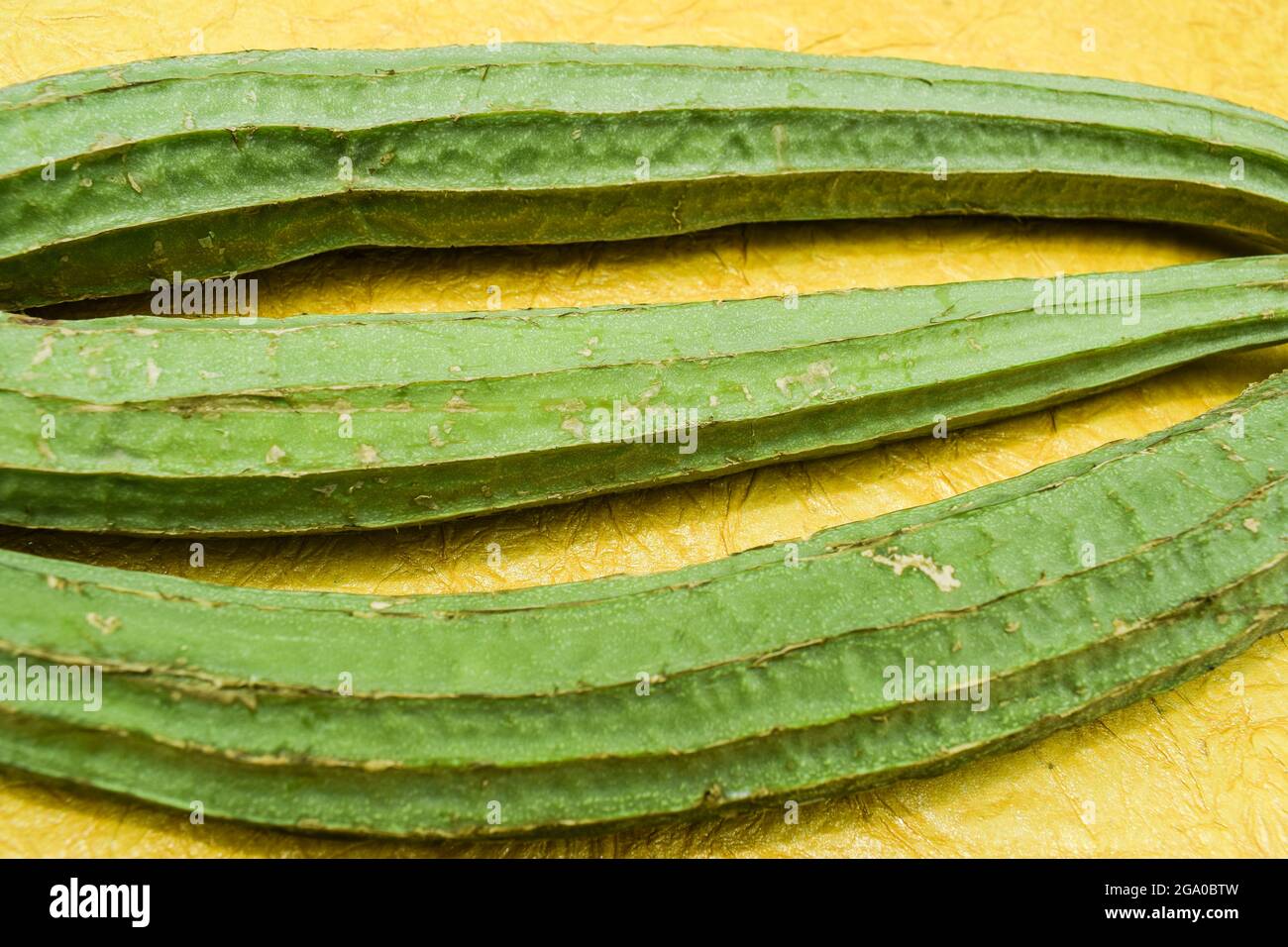 Ridge gourd vegetables long and thin on yellow background. Indian or ...