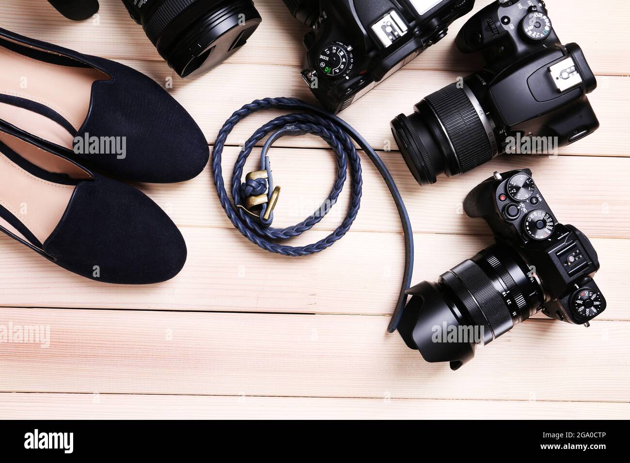 Modern cameras with female shoes and belt on wooden table, top view ...