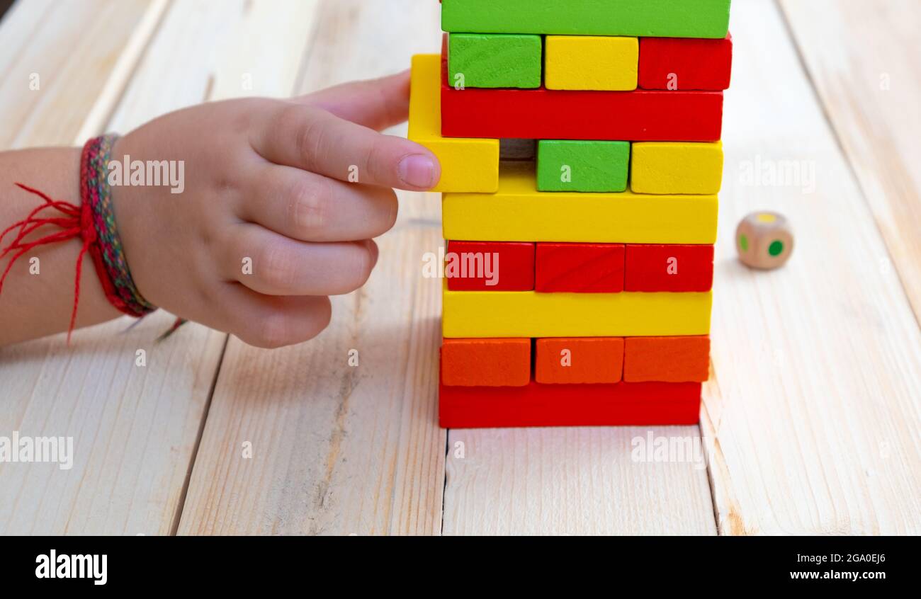 Close-up of a girl's hand holding a block from a wooden tower game ...