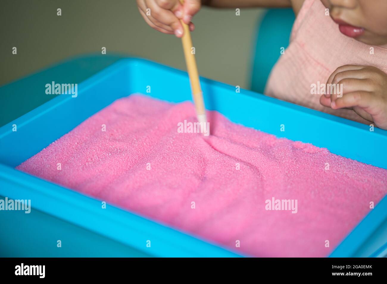 Little girl drawing a letter on colored pink sand Stock Photo - Alamy