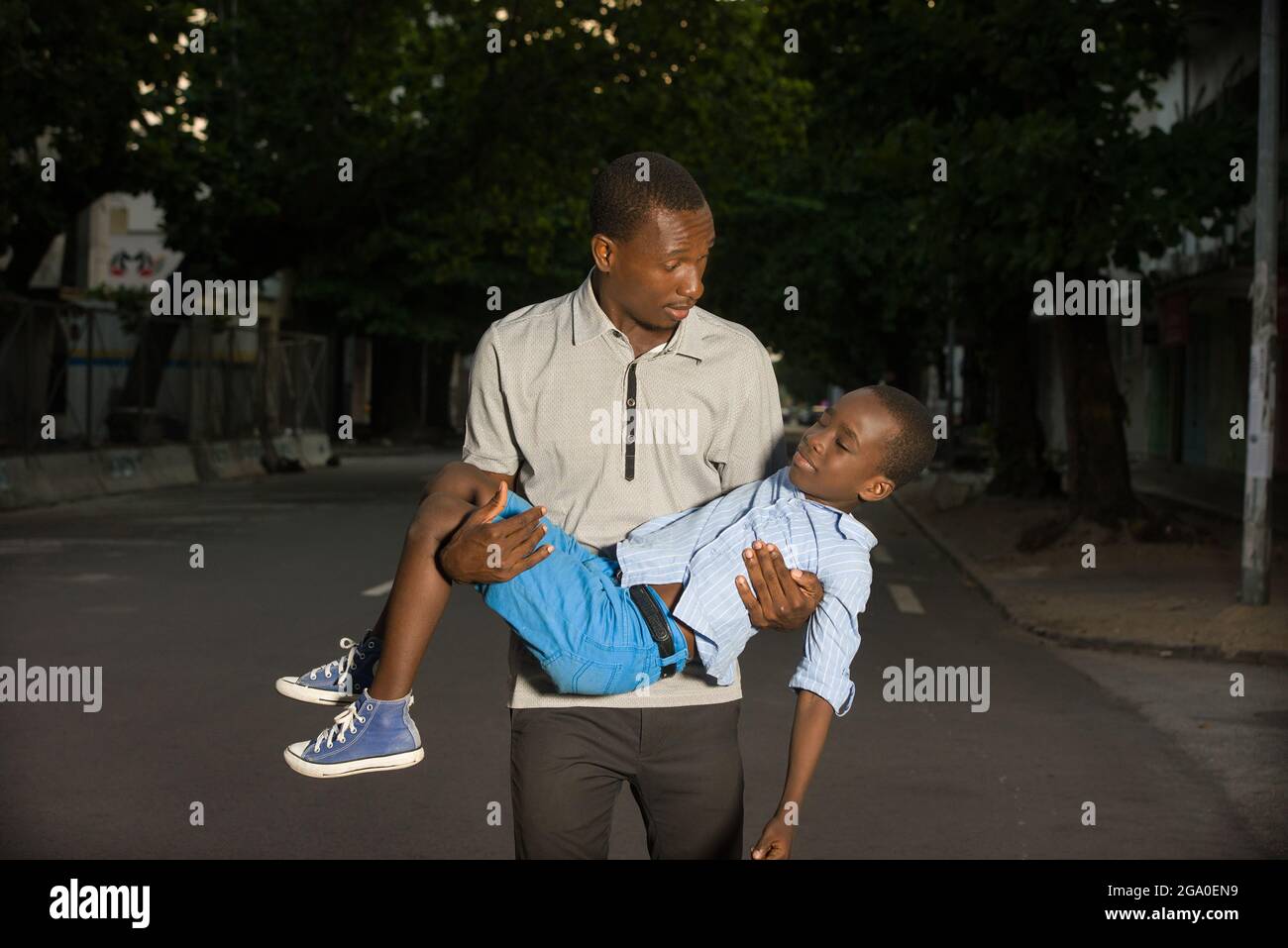 young anxious father carrying his injured boy in the emergency park ...