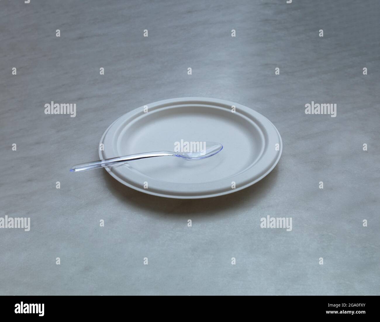 spoon and empty plastic plate for eating on a white marble table with ...
