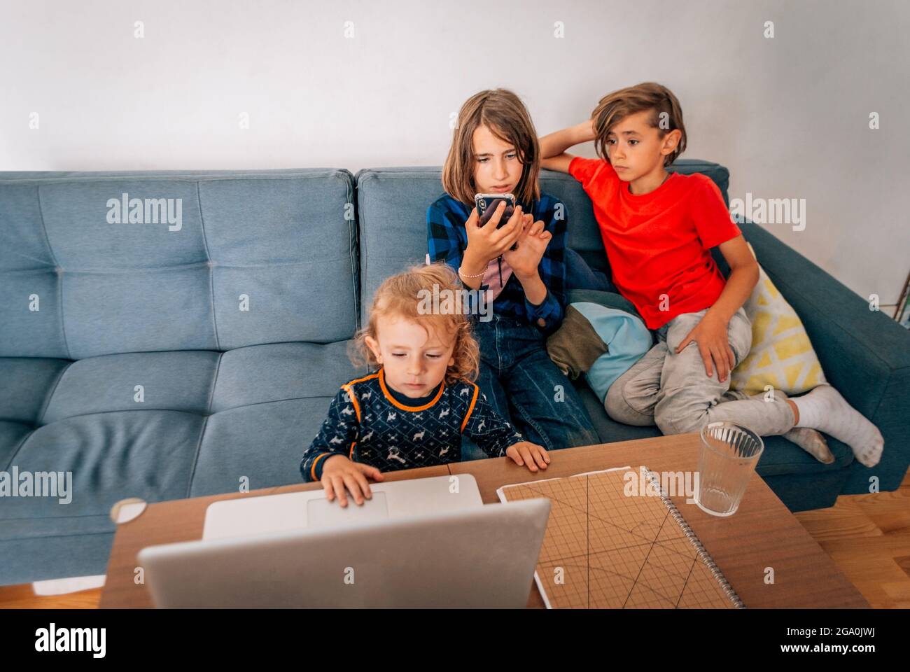 Three children watch cartoons and play on phone and laptop Stock Photo ...