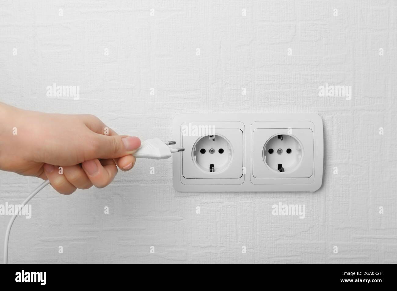 Hand putting plug in electricity socket close up Stock Photo - Alamy