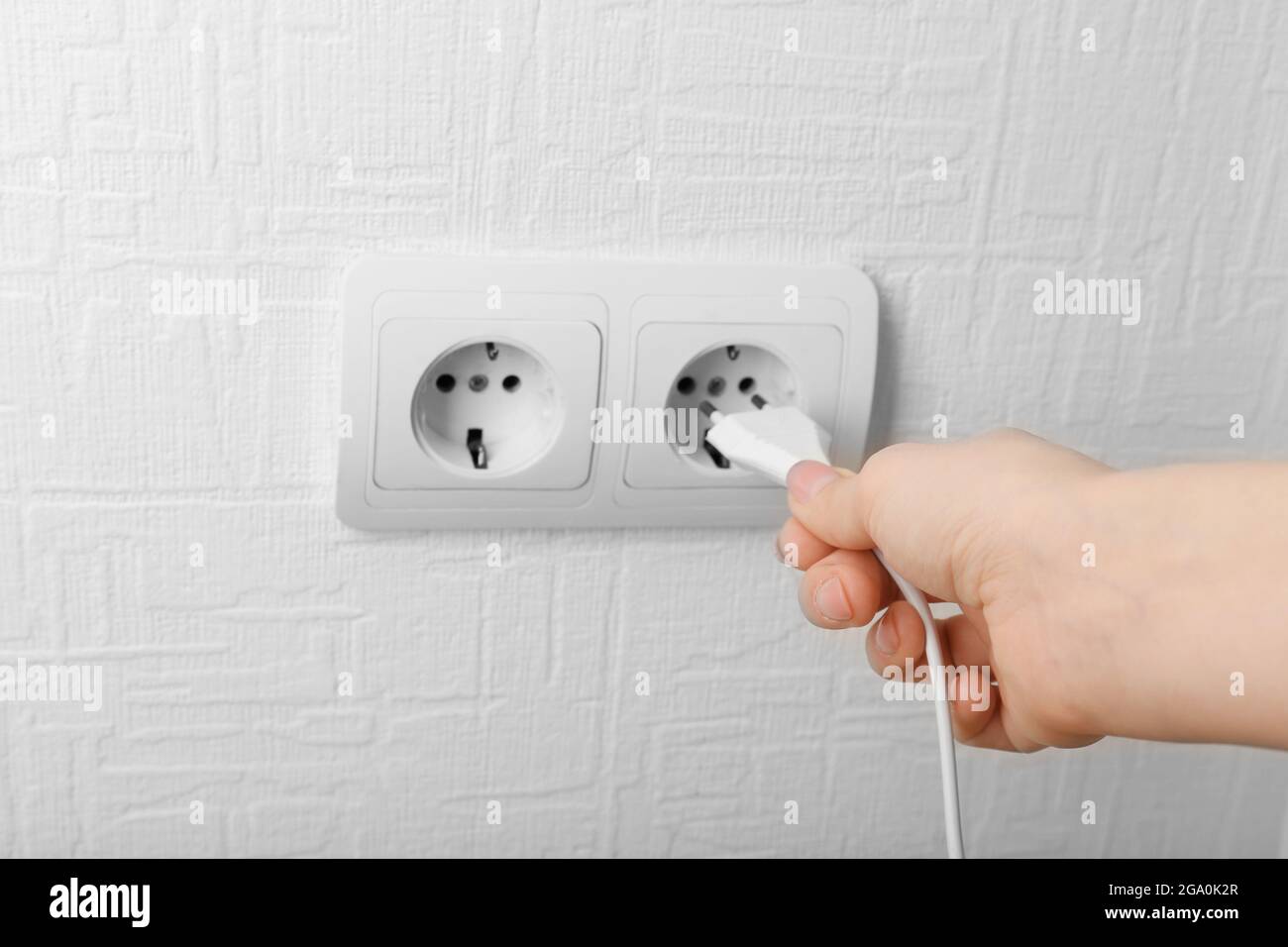 Hand putting plug in electricity socket close up Stock Photo - Alamy