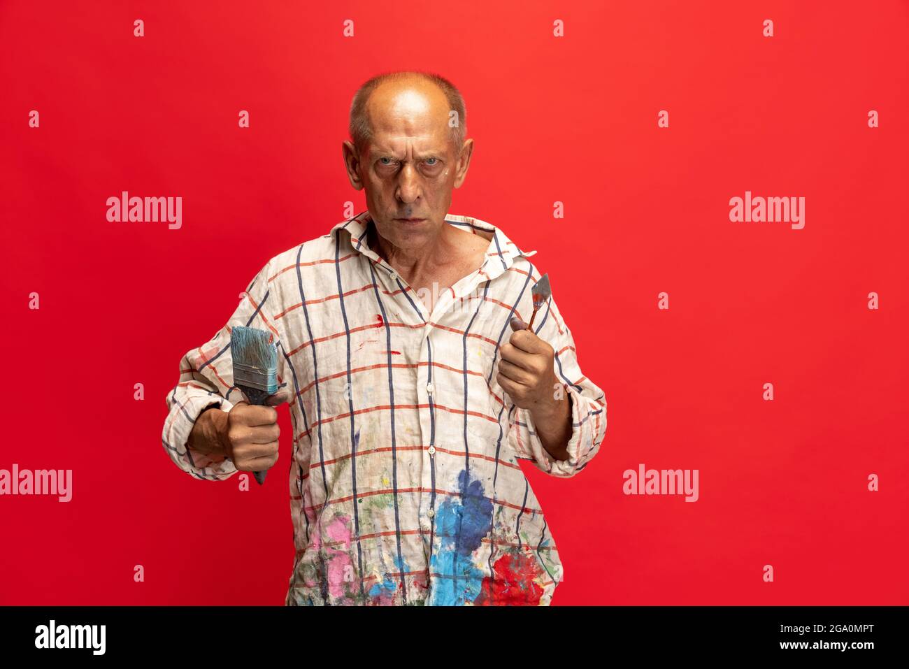 Mature or senior grey painter with a brush standing in front of camera ...