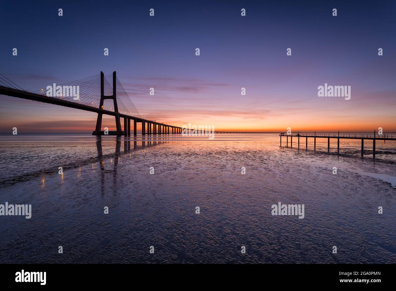 Vasco da Gama bridge over tagus river and a pier before sunrise in ...