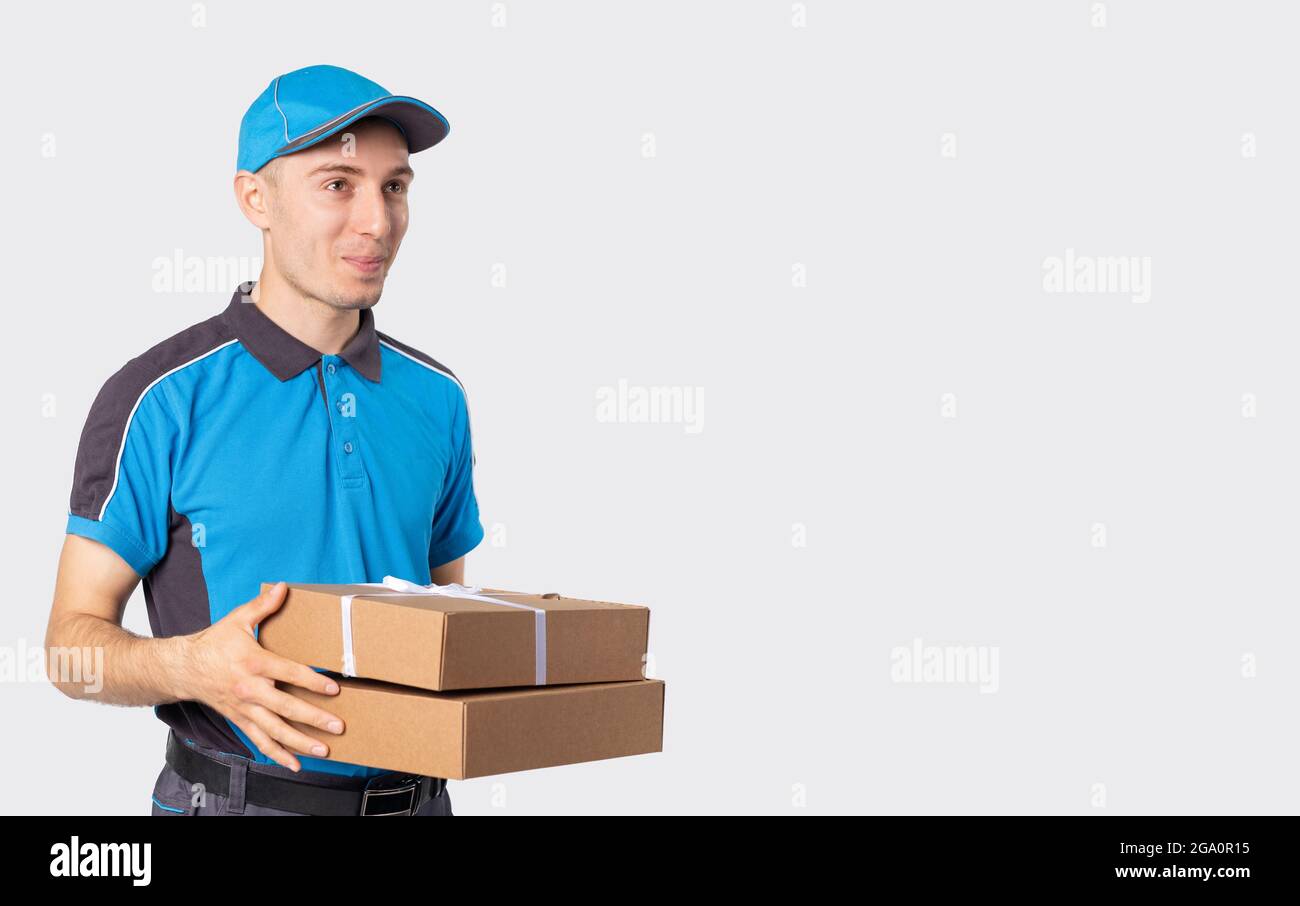The photo of a postman holding two carton box packages wearing blue ...
