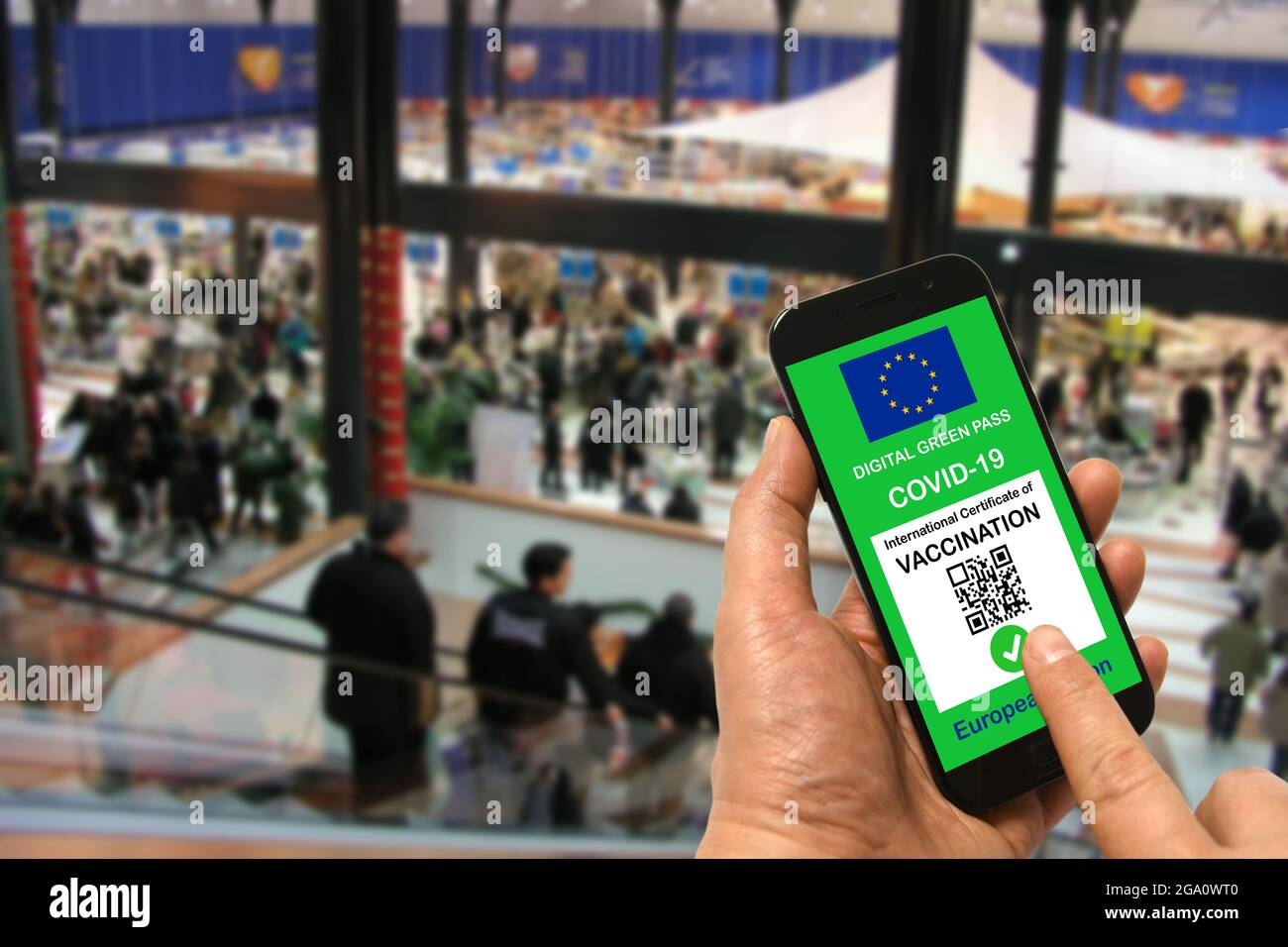 A man in a shopping mall holds a smartphone with the European Union ...