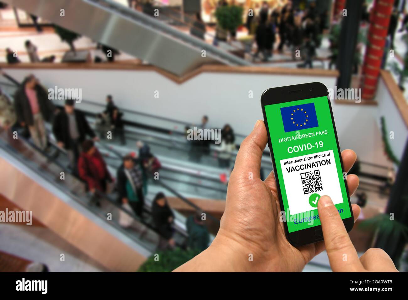 A man in a shopping mall holds a smartphone with the European Union ...