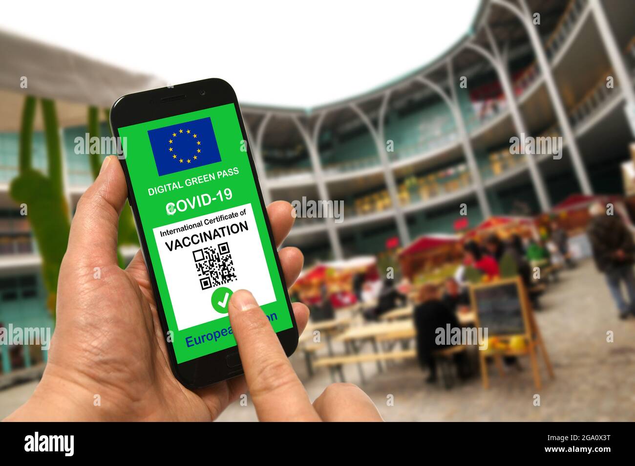 A man in a shopping mall holds a smartphone with the European Union ...