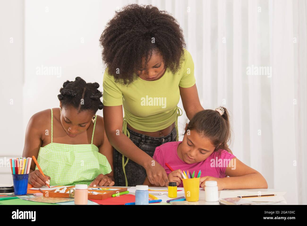 Two teachers helping to student girl to draw with colored pencils Stock ...