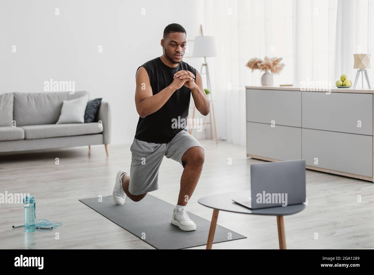 African Man Training At Laptop Doing Forward Lunge At Home Stock Photo ...