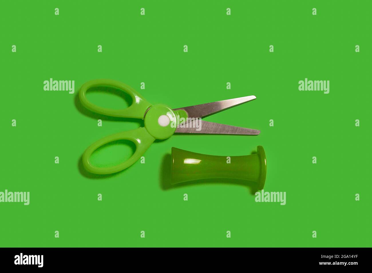 scissors with a cap on a green background Stock Photo - Alamy