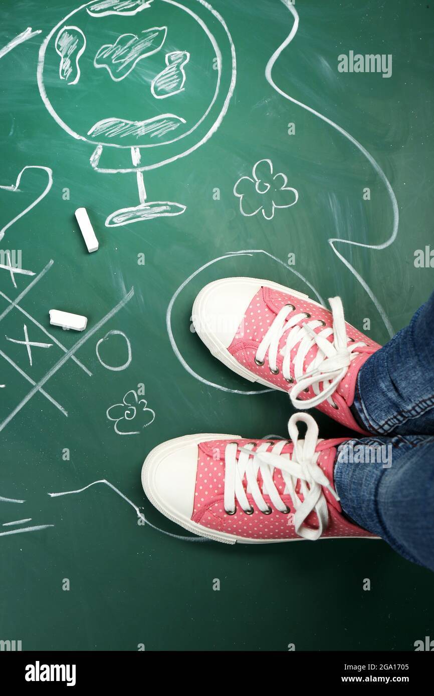 Female feet on blackboard background with inscriptions and sketches ...