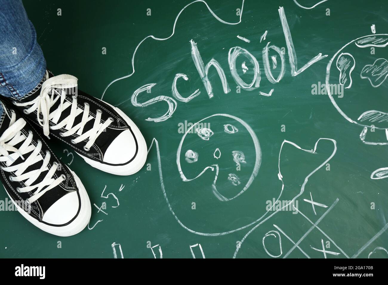 Female feet on blackboard background with inscriptions and sketches ...