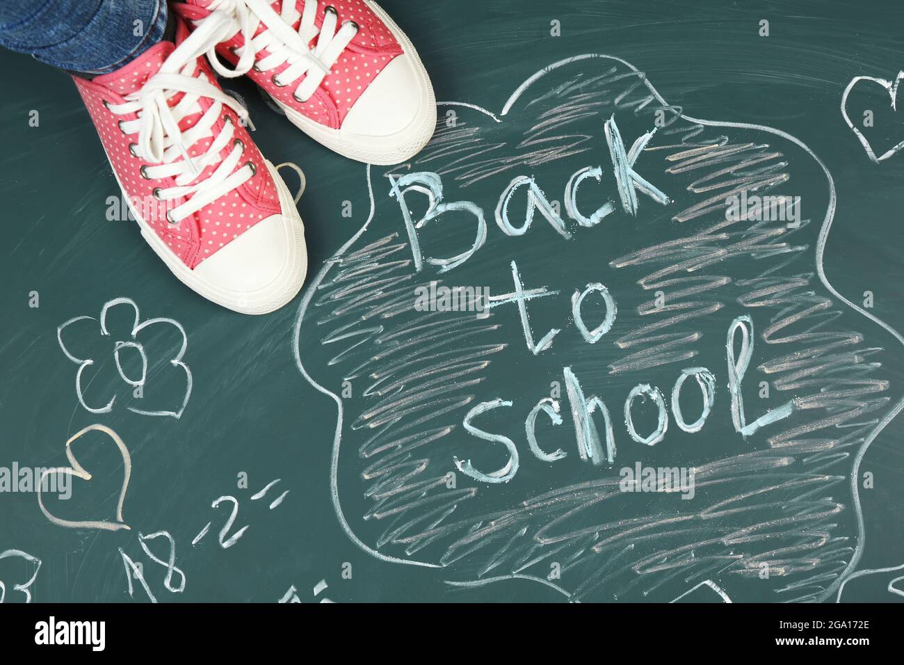 Female feet on blackboard background with inscriptions and sketches ...