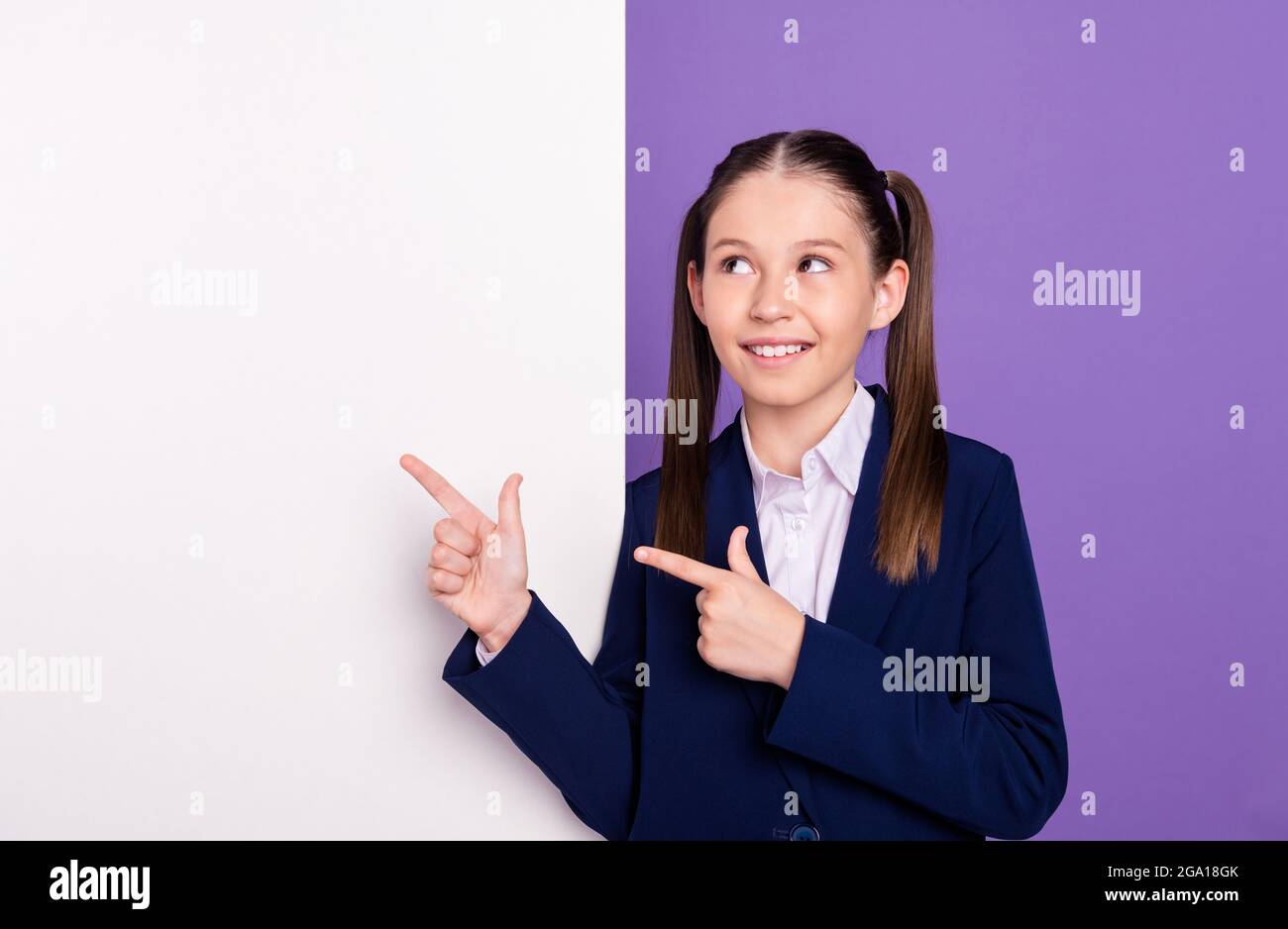 Photo of excited sweet school girl wear blue uniform pointing fingers ...