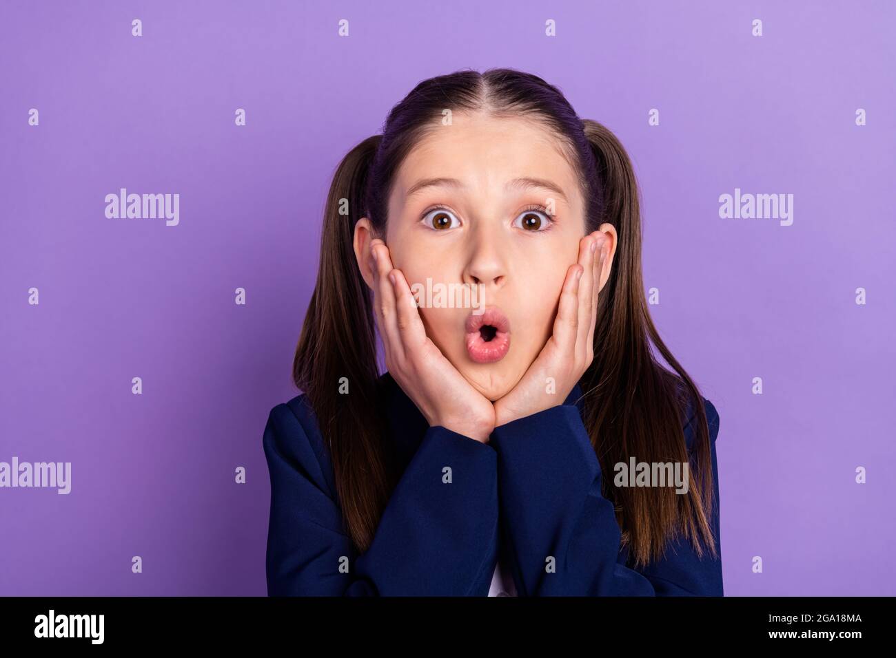Photo of adorable shocked school girl wear blue uniform arms cheeks big ...