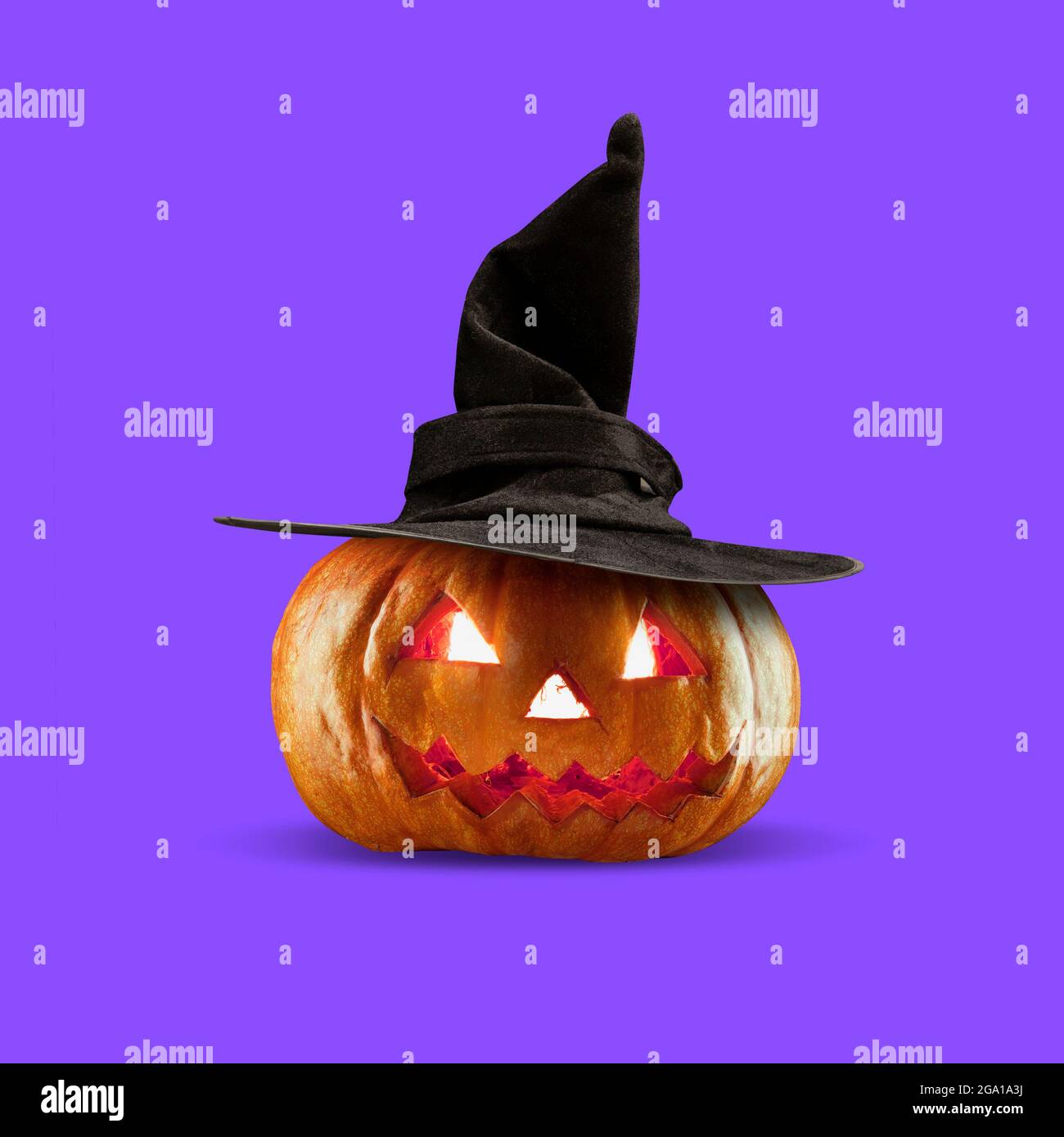 Scary Halloween pumpkin under black witch hat isolated on purple ...