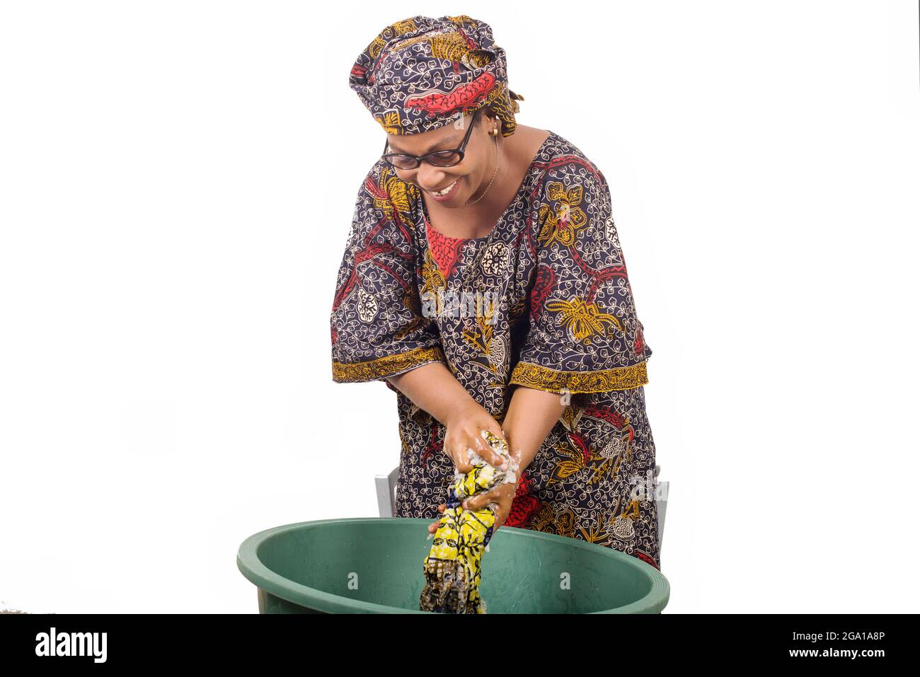 African woman standing above the laundry bowl washing clothes isolated ...