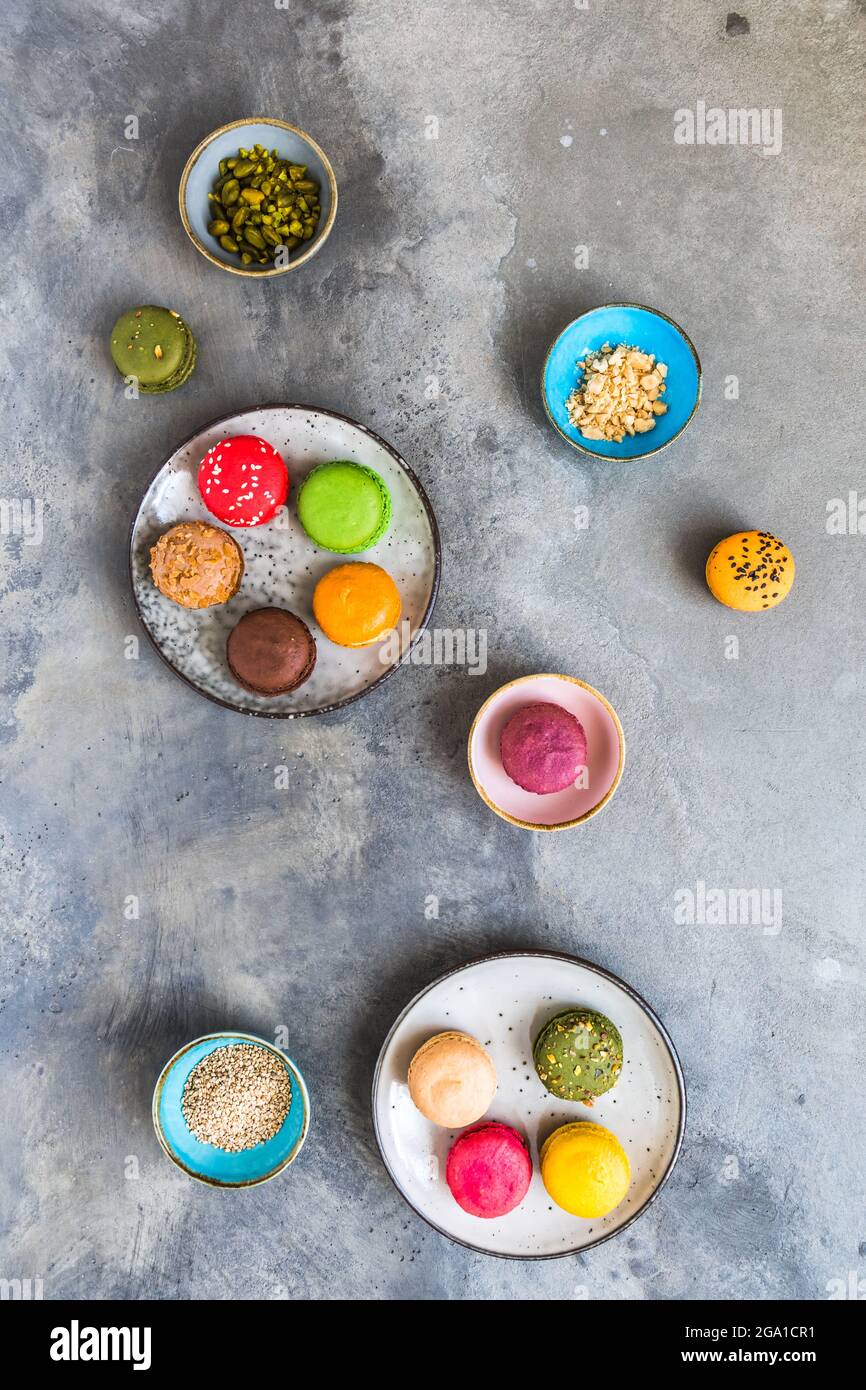 Colorful macarons and bowls with toppings on gray concrete background ...