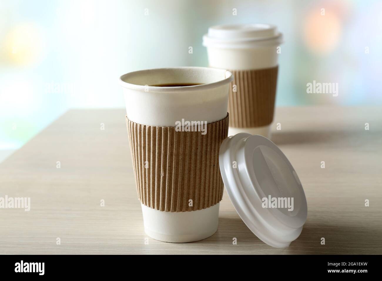 Paper cups of coffee on table on bright background Stock Photo - Alamy