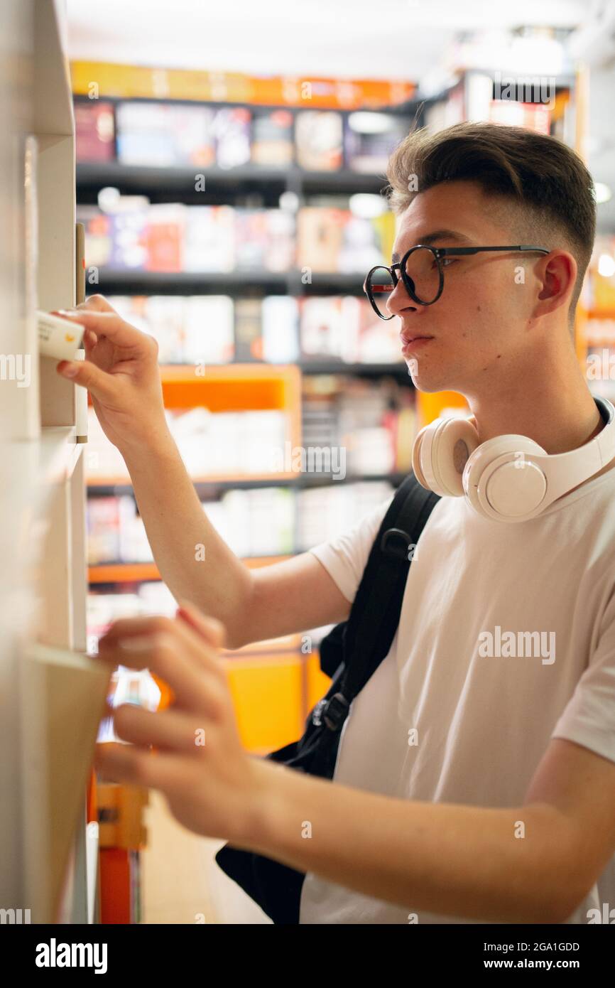 The male college student with book standing near shelf in library Stock ...